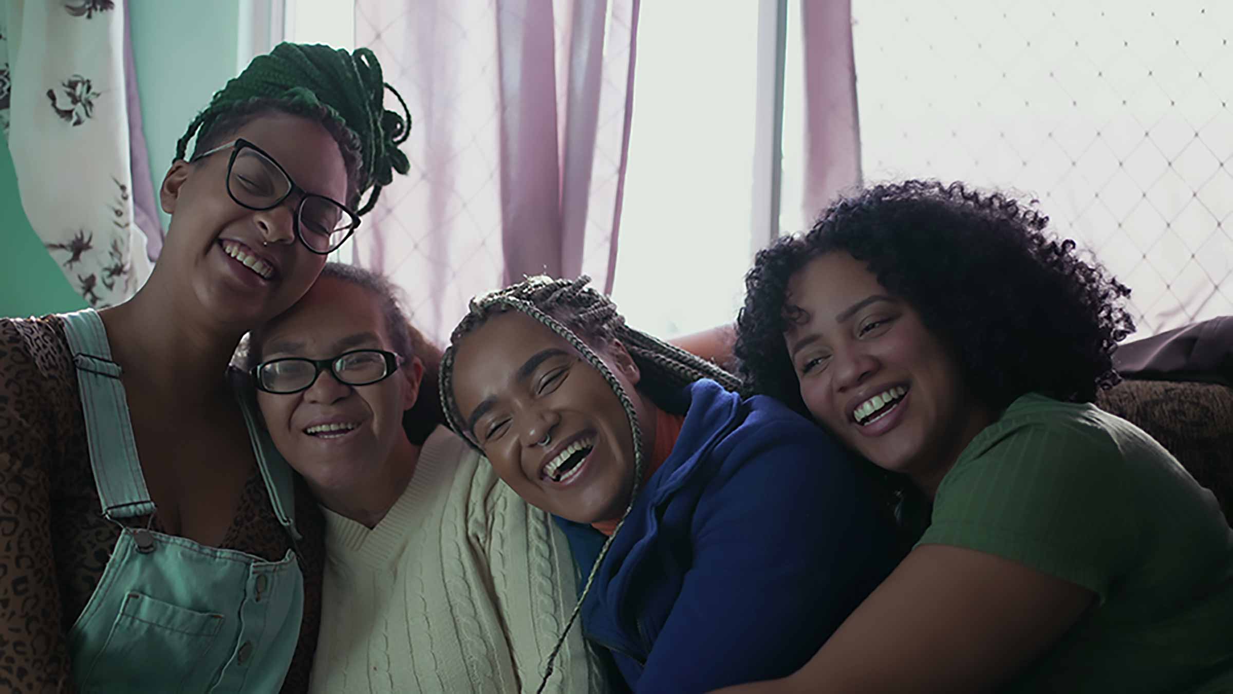 Four women smile and embrace