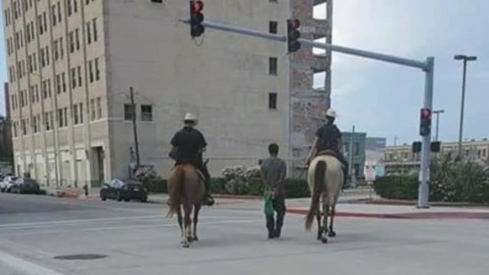 Mounted officers use rope to lead handcuffed man along Texas street