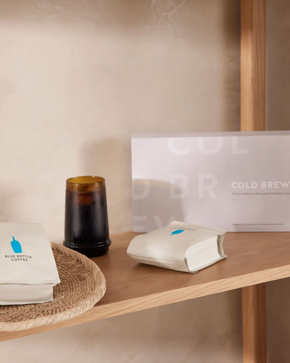 Cold brew set, glass of cold brew and bags of whole bean.