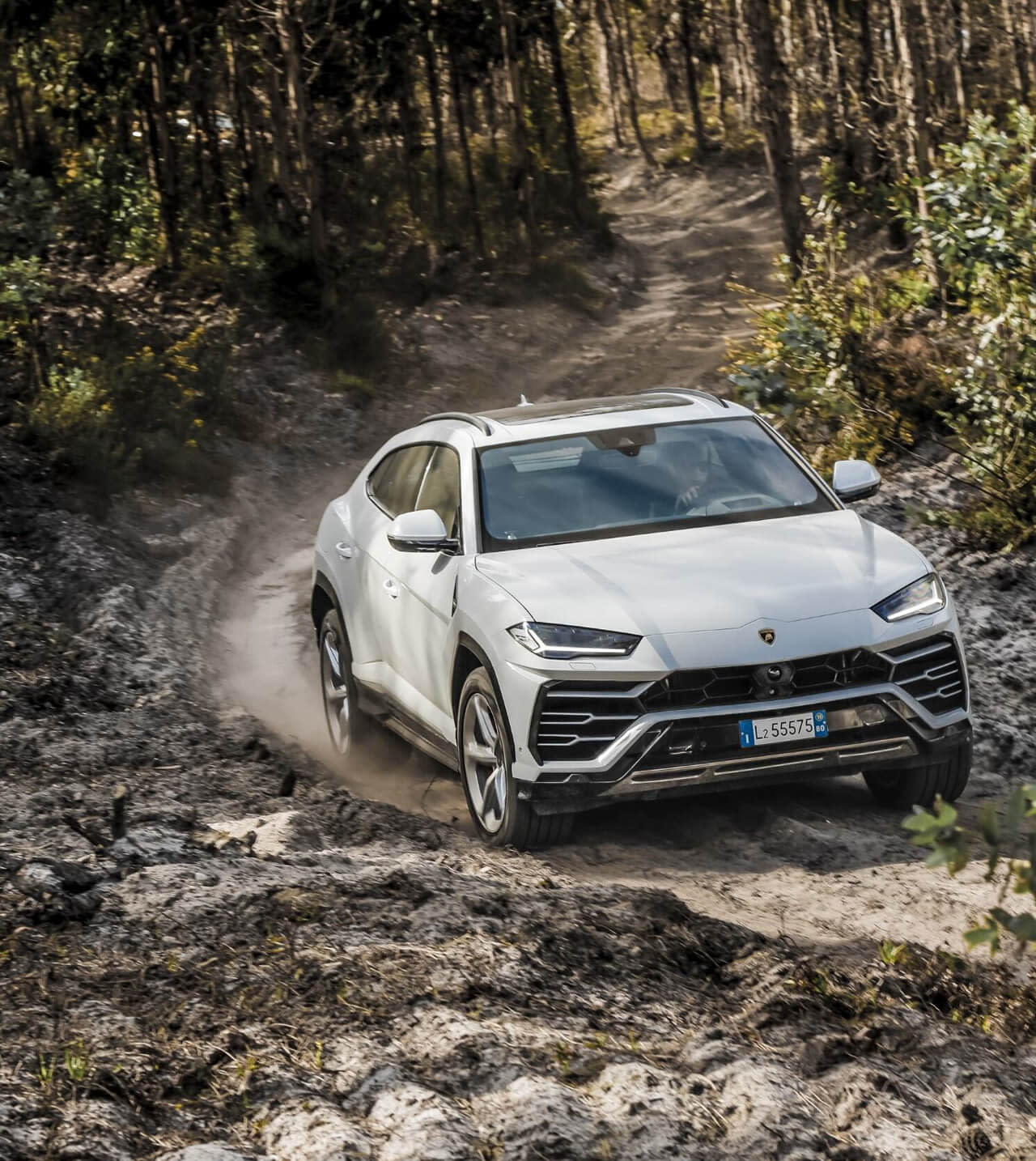 A Lamborghini Urus driving on a beach.