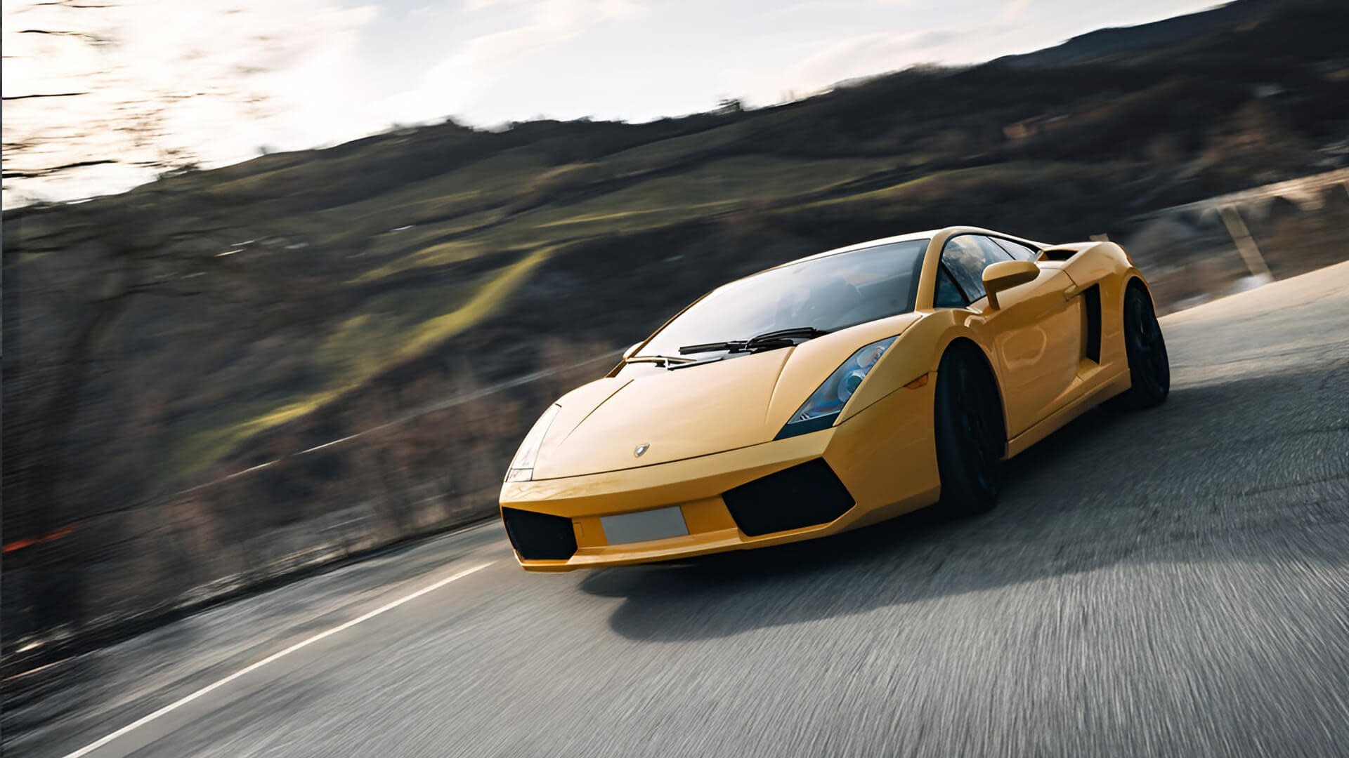 The front view of a Lamborghini Gallardo driving down a scenic road